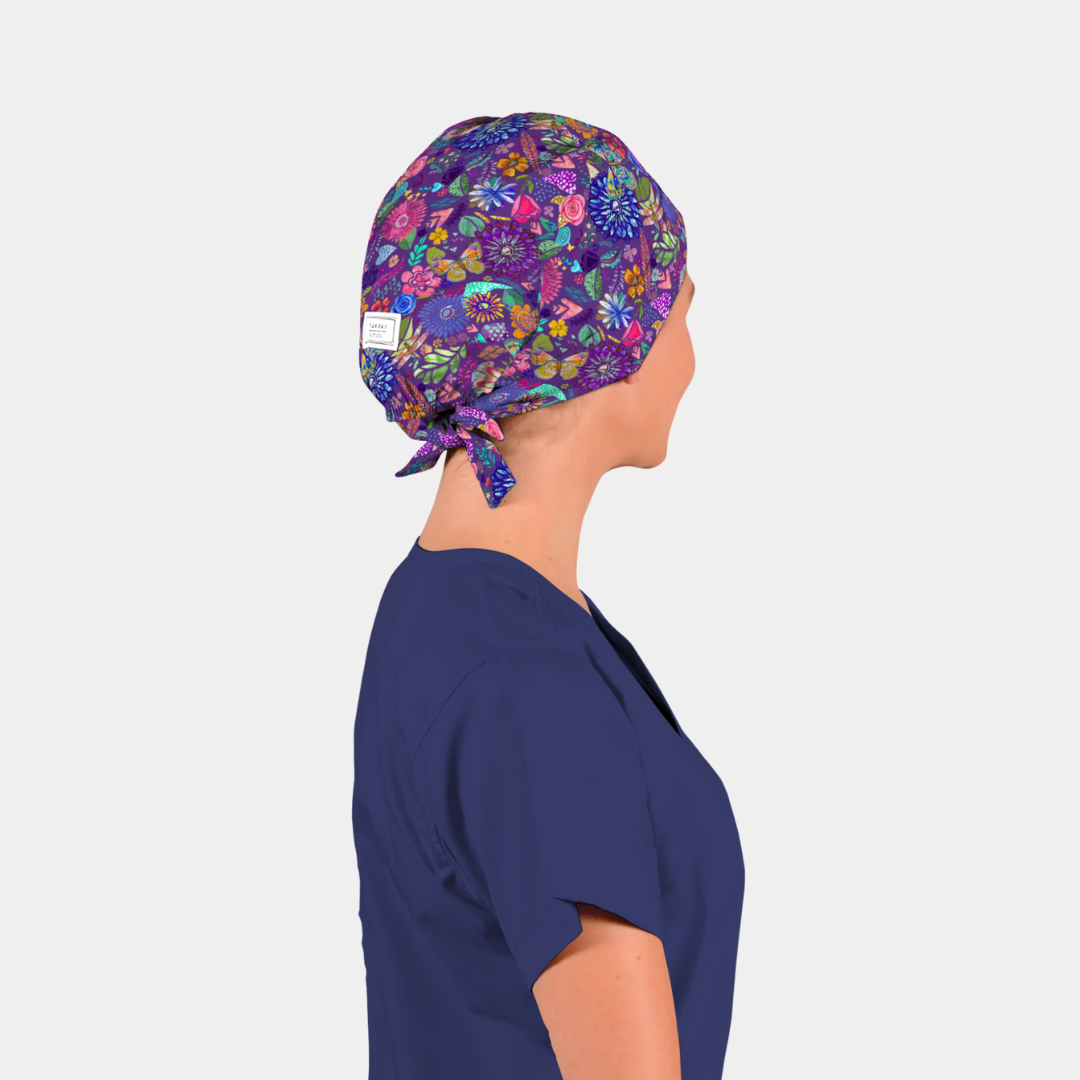 Person wearing a colorful purple floral scrub cap on a plain background