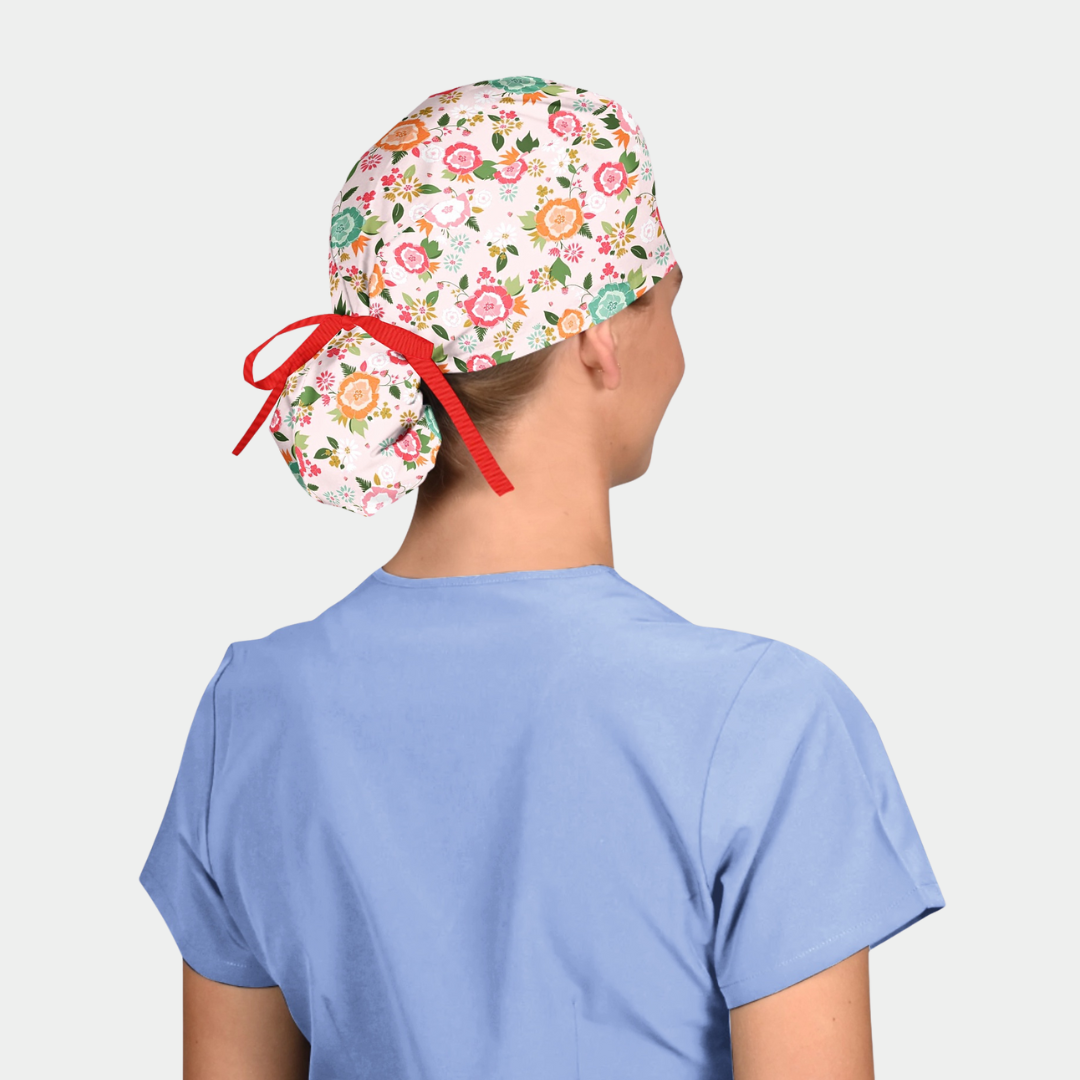 Person wearing a pink floral scrub cap with a red ribbon on a plain ...